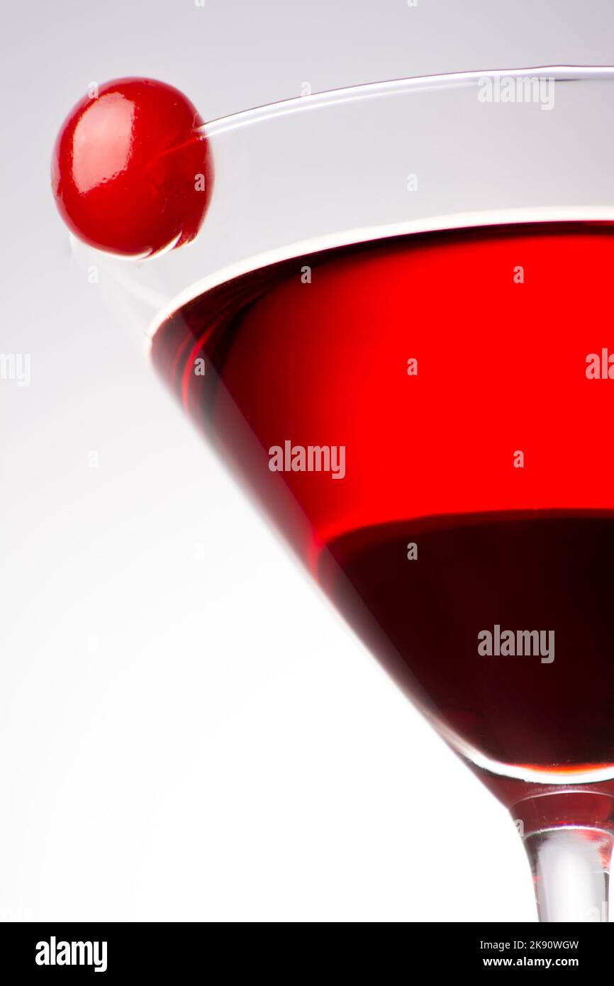 A vertical shot of a red alcoholic cocktail with a cherry on the glass ...