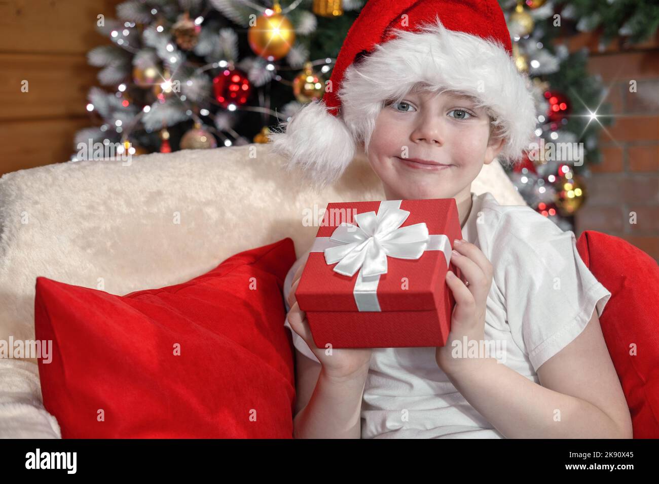 Merry Christmas kids. A boy in a Santa hat with a gift from Santa Claus ...