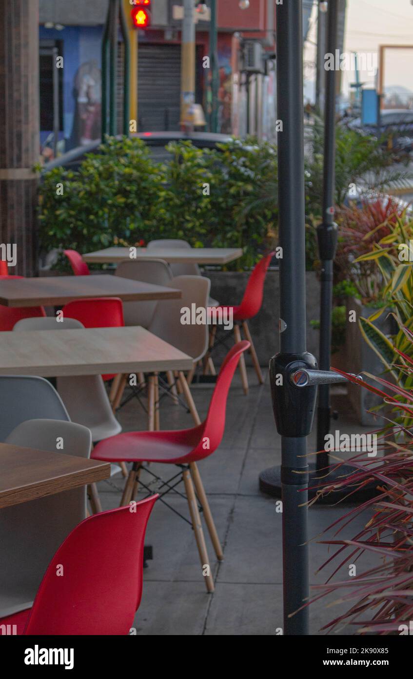 A vertical shot of red and gray chairs set up by square tables in an ...
