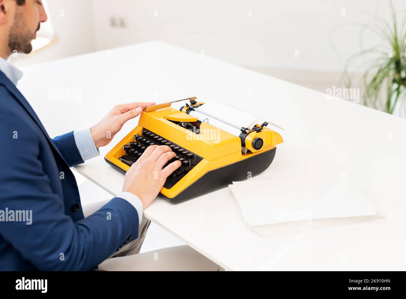Close-up of a man typing on retro yellow typewriter while sitting at ...