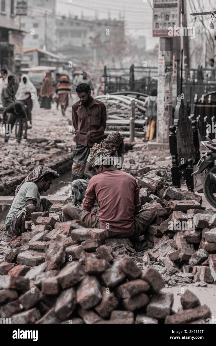 The street scene of workers breaking bricks by hand to reuse them on ...