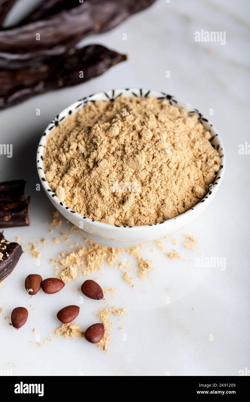 Carob pods and carob powder over a marble background Stock Photo - Alamy