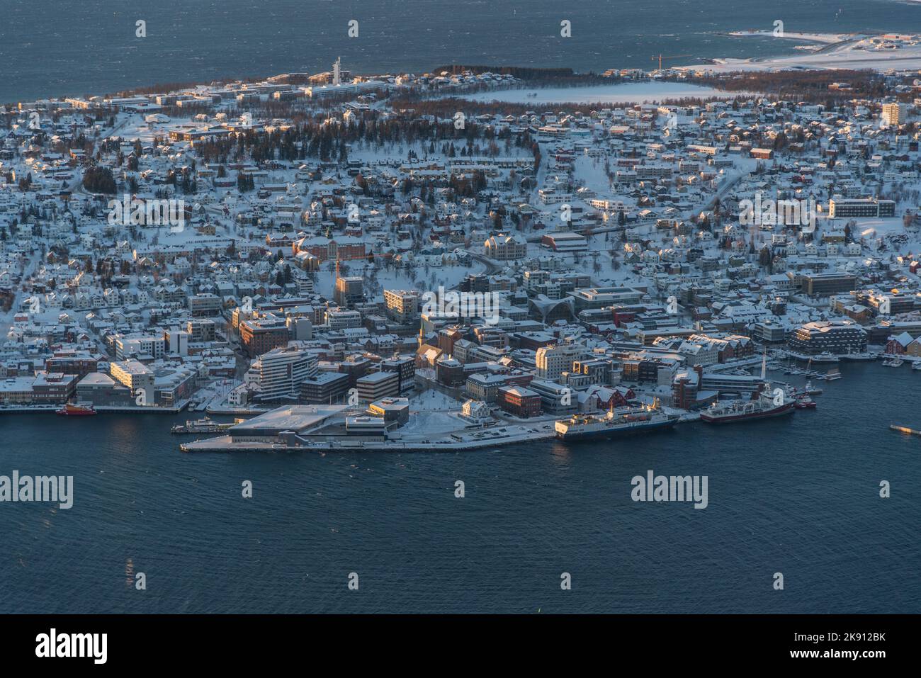 An aerial view of Tromso city next to a sea in Norway during the sunset ...