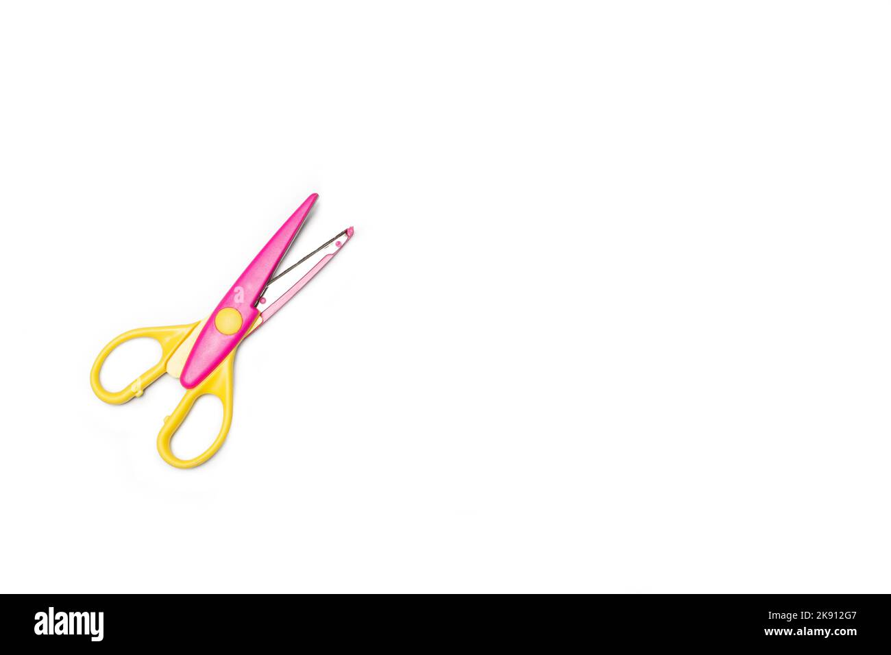 Plastic pink and yellow scissors on a pink background with copy space ...