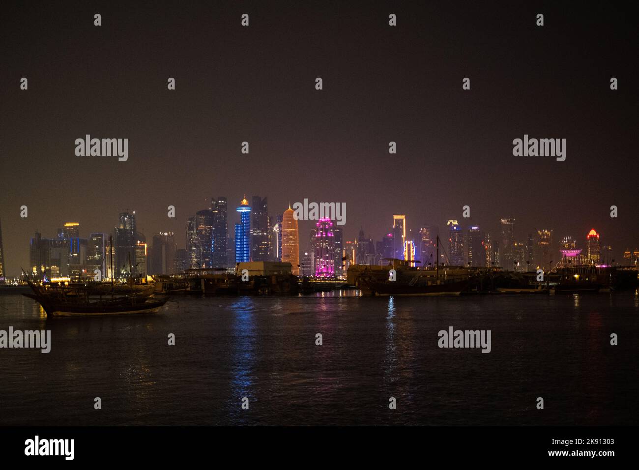 Slightly hazy Doha skyline at night, viewed across the water, from the ...