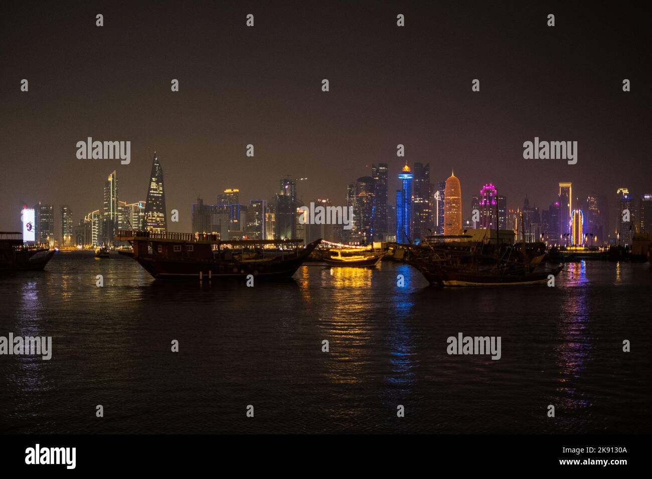 Slightly hazy Doha skyline at night, viewed across the water, from the ...