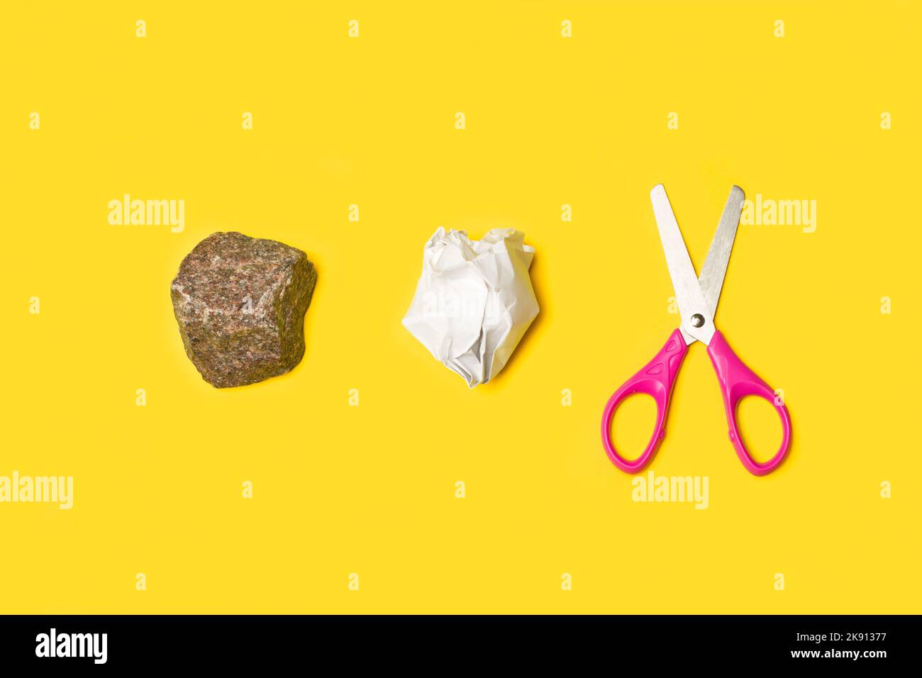 A stone, crumpled paper ball, and scissors on a yellow background Stock ...