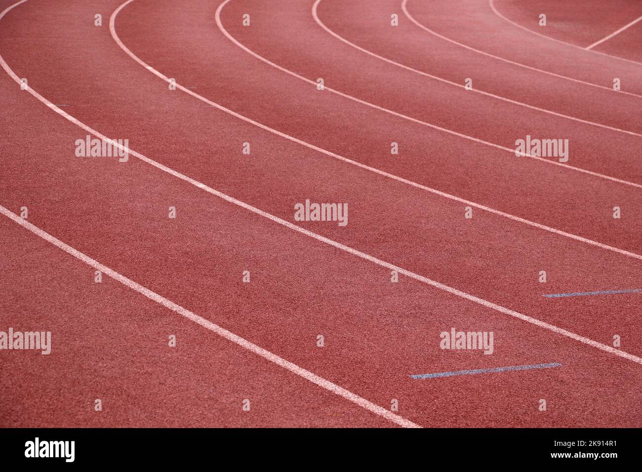 White lines forming lanes of an athletics track made of red rubber ...