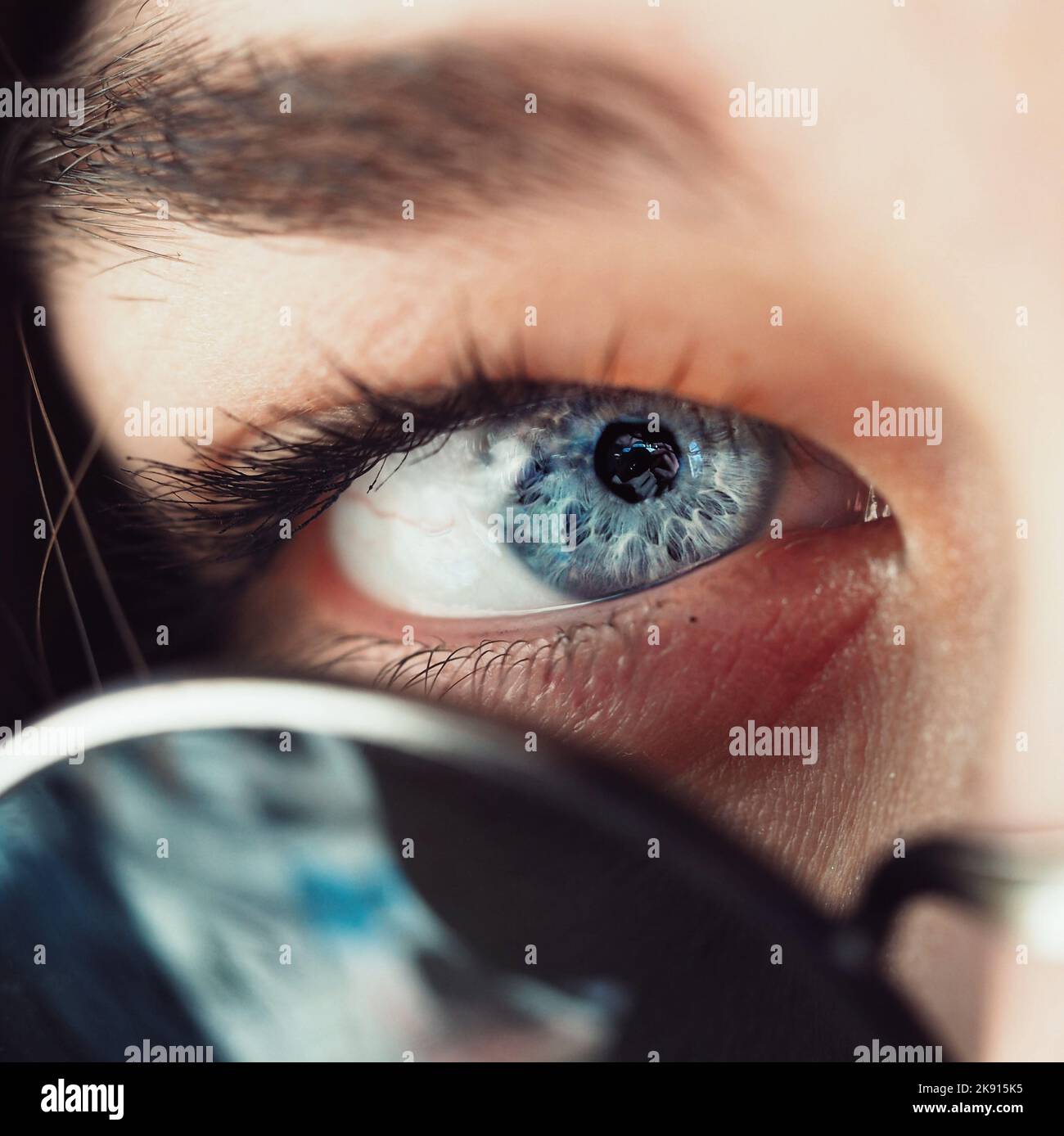 A macro of a blue eye with a slight view of sunglasses and the ...