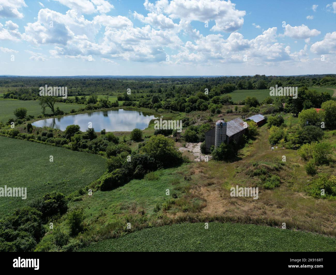 An aerial view of a farm with a lagoon and a green field under a cloudy ...