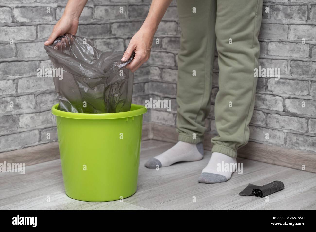 a woman changes a garbage bag in a bucket. woman tearing off a trash ...
