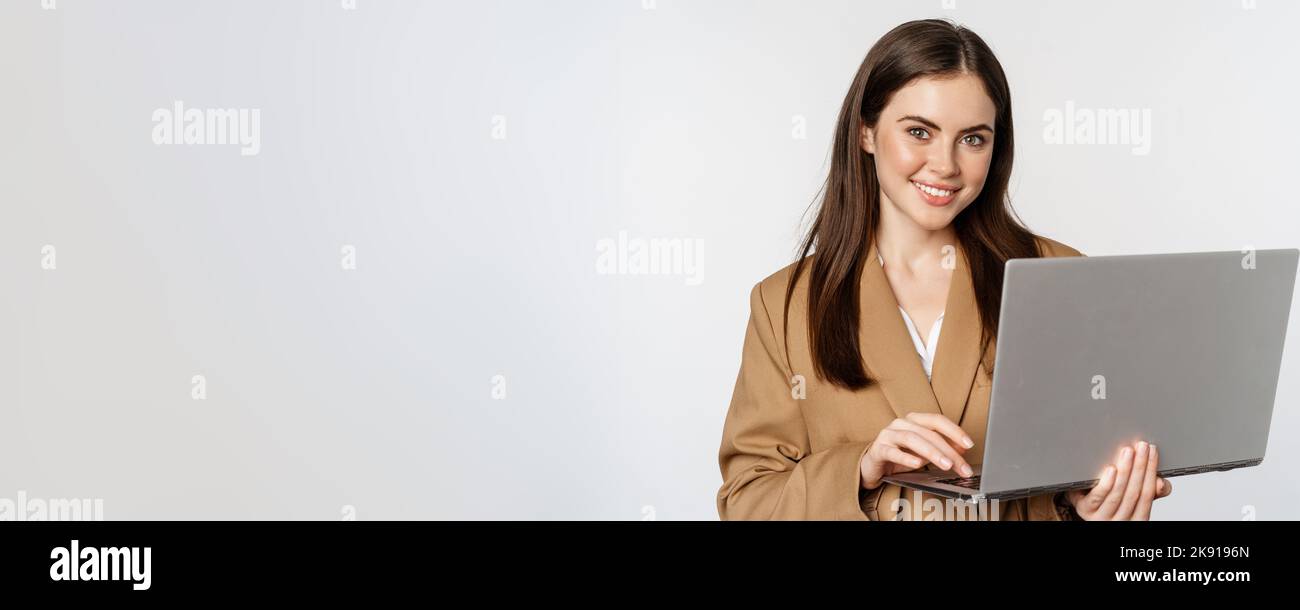 Portrait of corporate woman working with laptop, smiling and looking ...