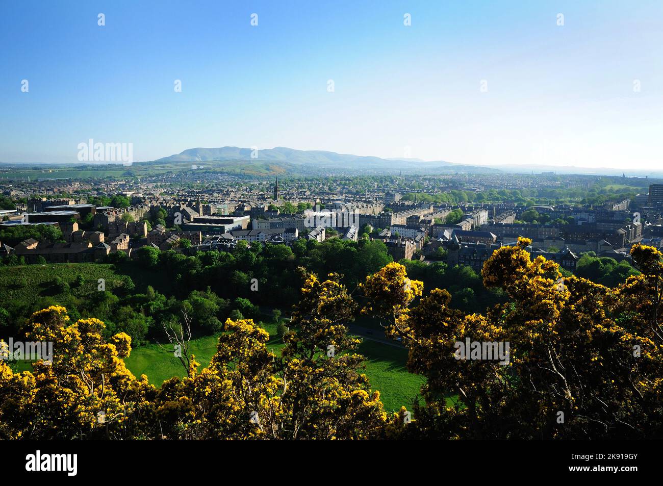 An aerial view of the Edinburgh city with a green field on a sunny day ...