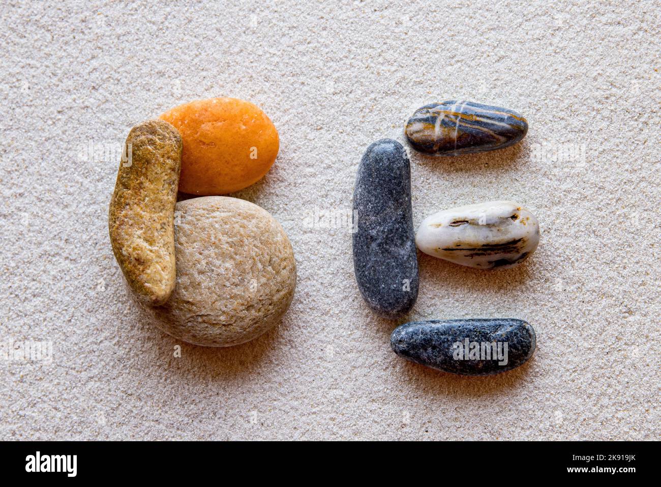 The word "Be" written using colored stones on white sand Stock Photo ...