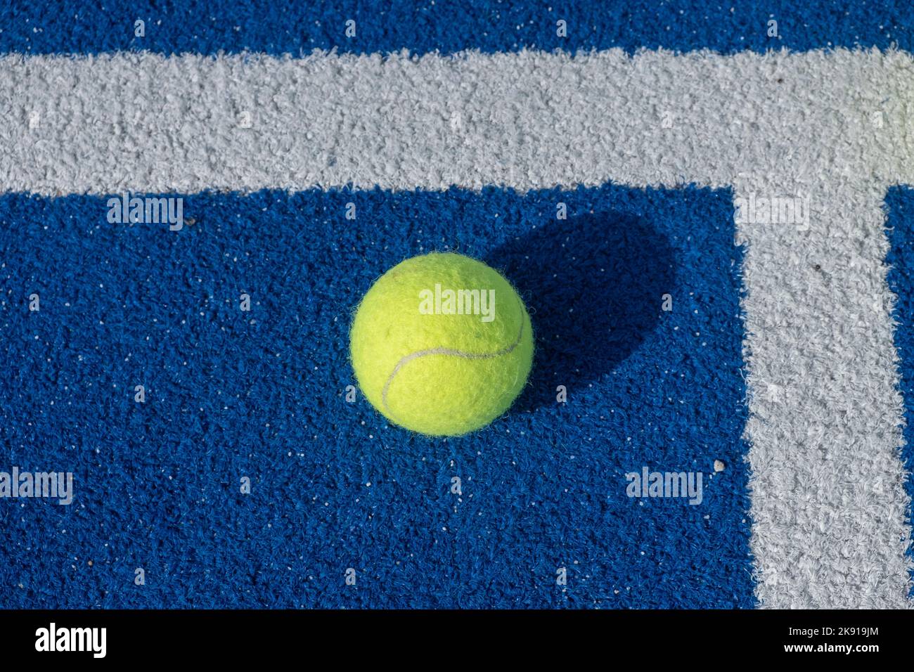 blue paddle tennis court, one ball next to the line, one ball next to ...