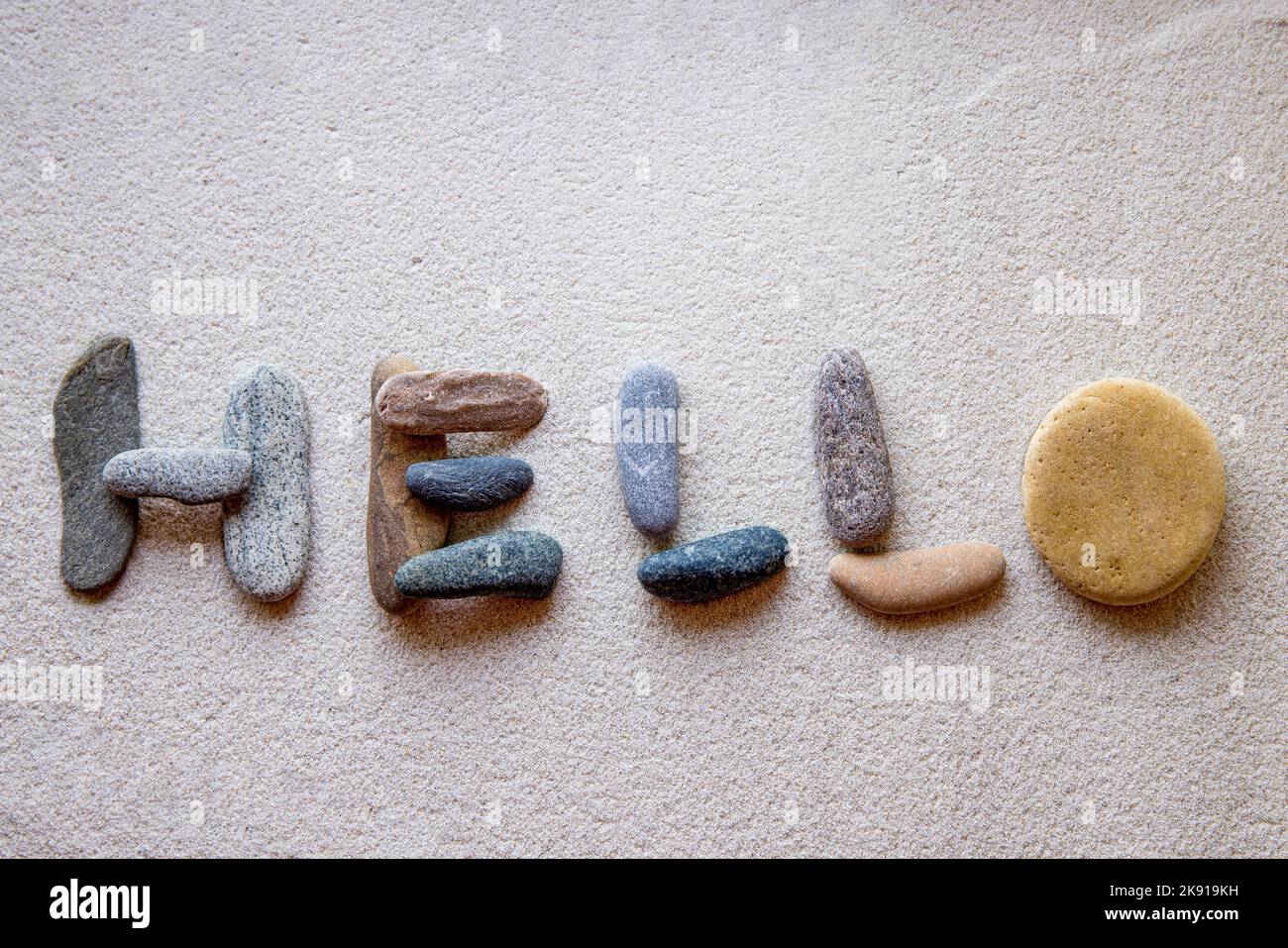 The word "Hello" written using colored stones on white sand Stock Photo ...