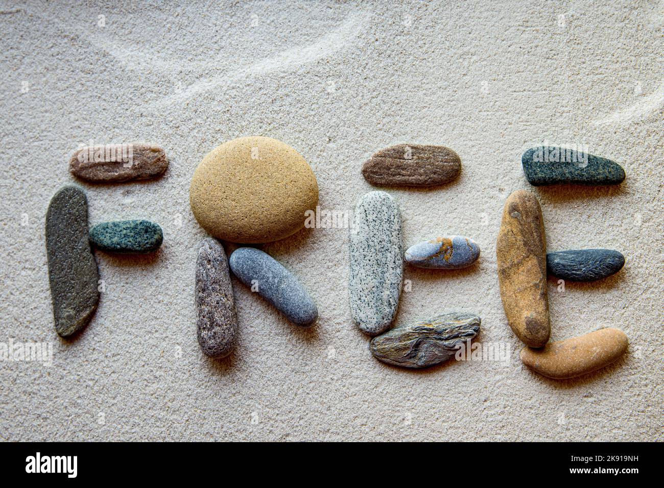 The word "Free" written using colored stones on white sand Stock Photo ...