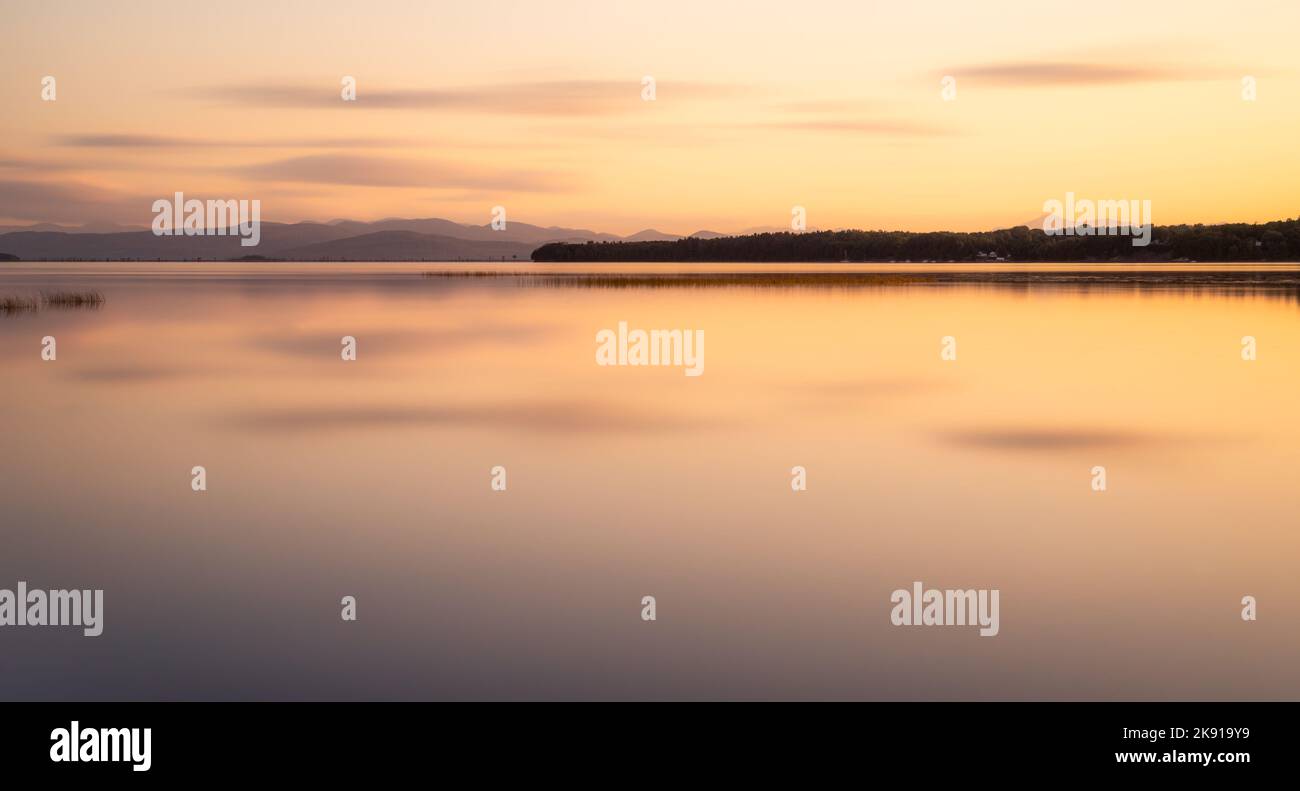 The view of a beige sunset sky reflecting on the Lake Champlain Stock ...