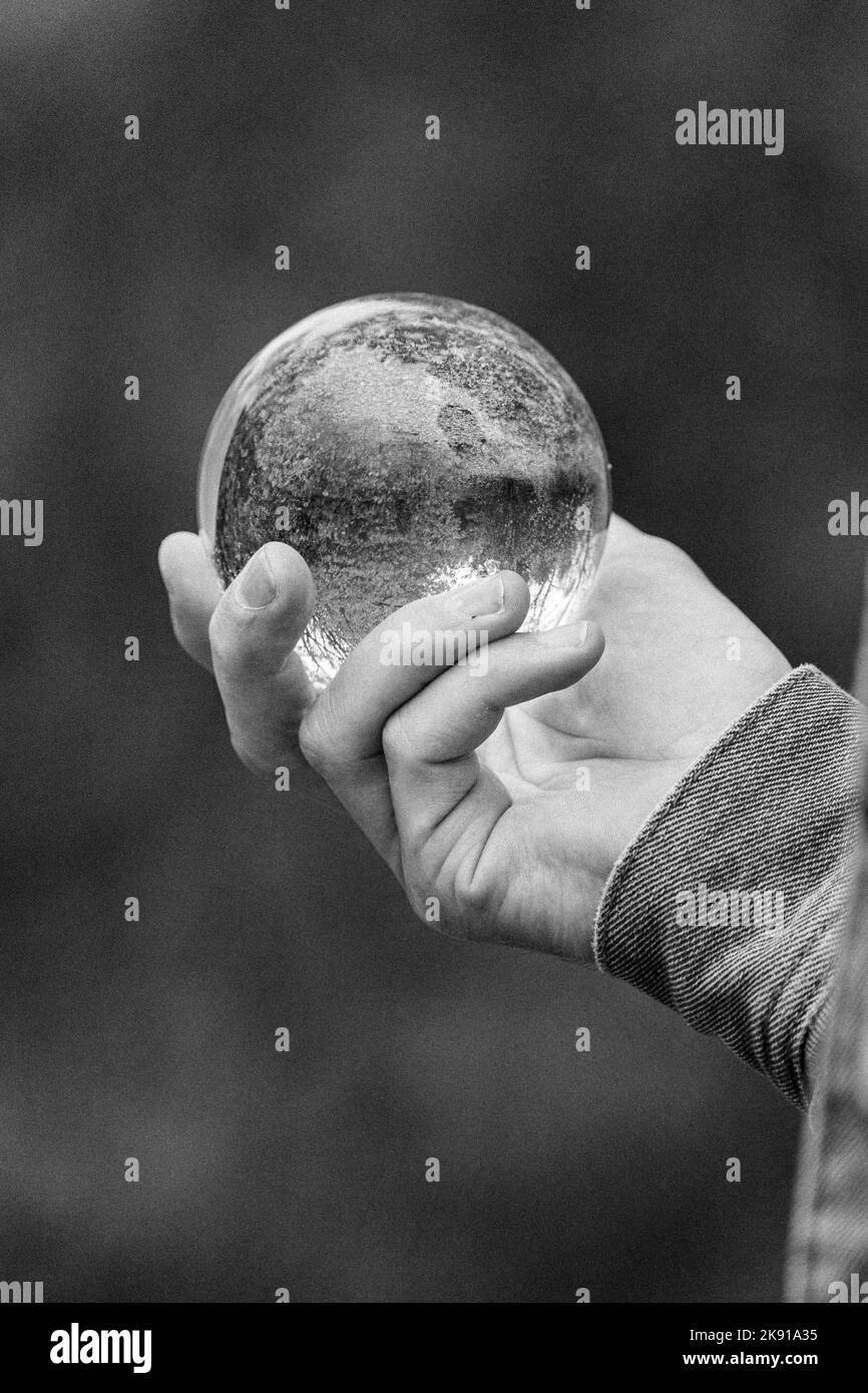 A vertical grayscale shot of a person's hand holding a crystal-clear ...