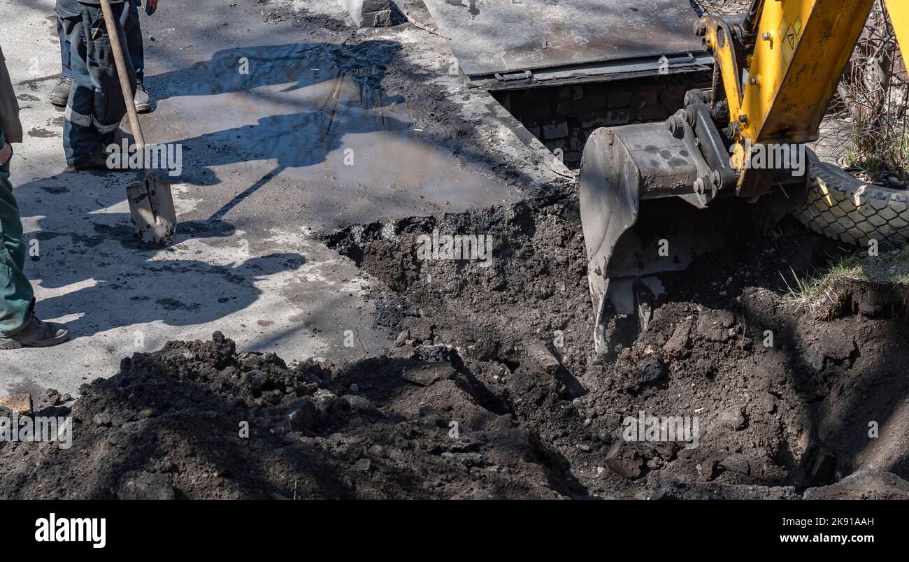 view of an excavator bucket digging the ground, breaking the asphalt ...