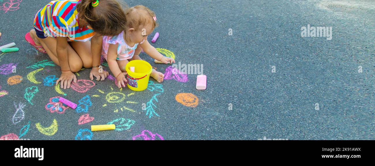 The child draws with chalk on the asphalt. Selective focus. Kids Stock ...