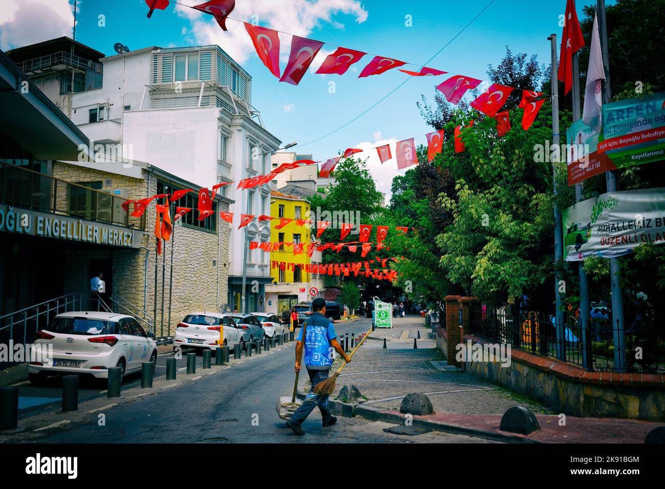 A street in Turkey with a man cleaning the streets and flags hung on ...