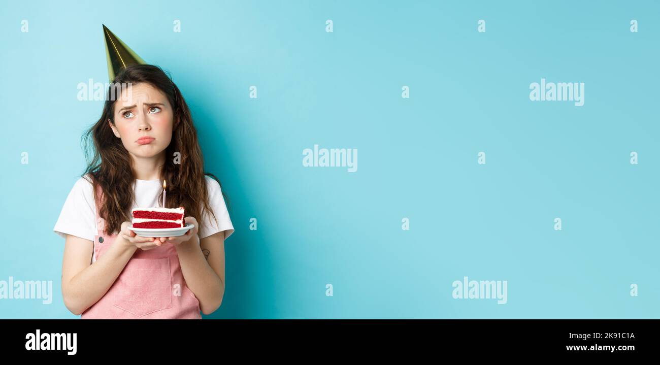 Holidays and celebration. Sad girl in party hat holding birthday cake ...