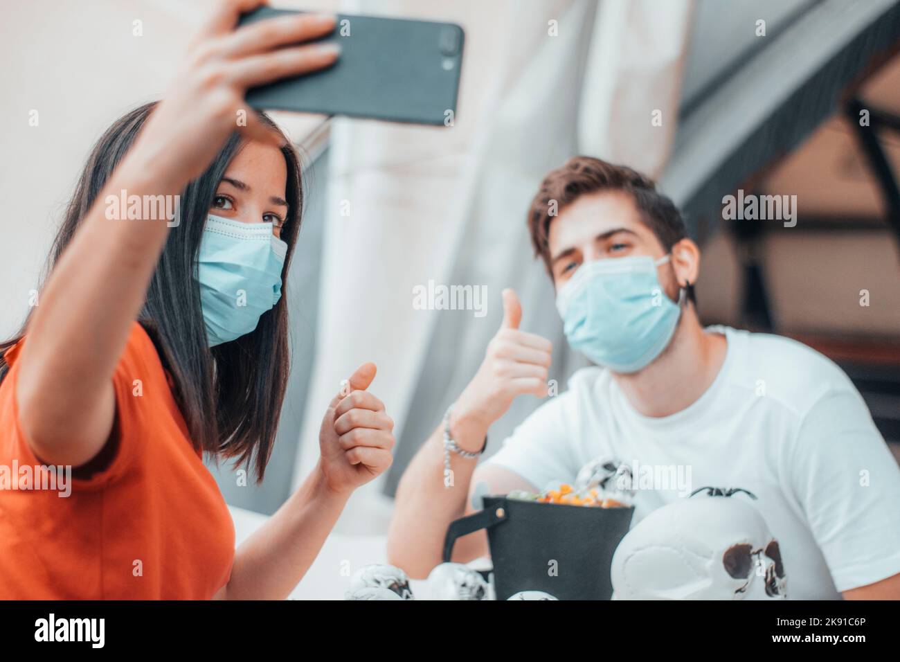 Two friends boy and girl taking a selfie in medical masks while making ...