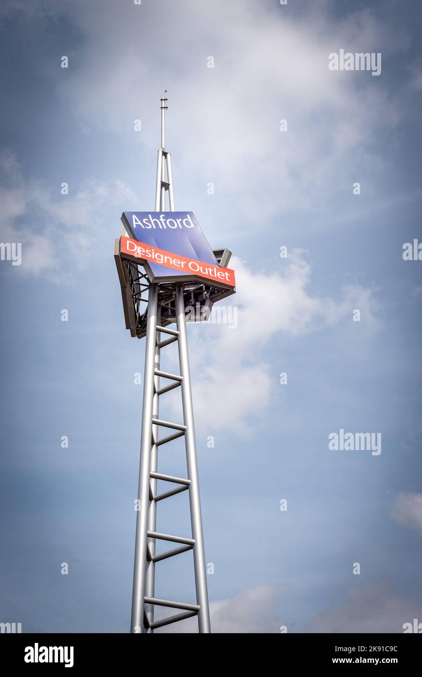 Ashford Outlet Centre tall blue and red entrance sign on bright blue ...