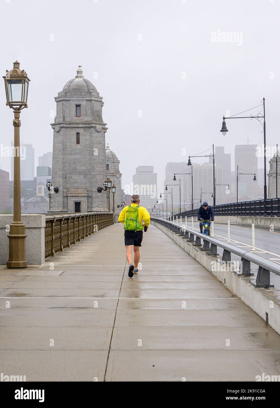 A backs shot of a man running along Longfellow Bridge in a rainy day ...