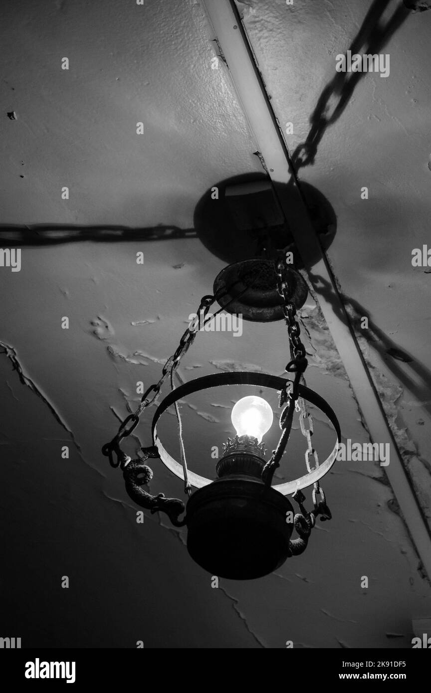 Old lamp hanging from damaged ceiling. Decay, poverty concepts. Black ...