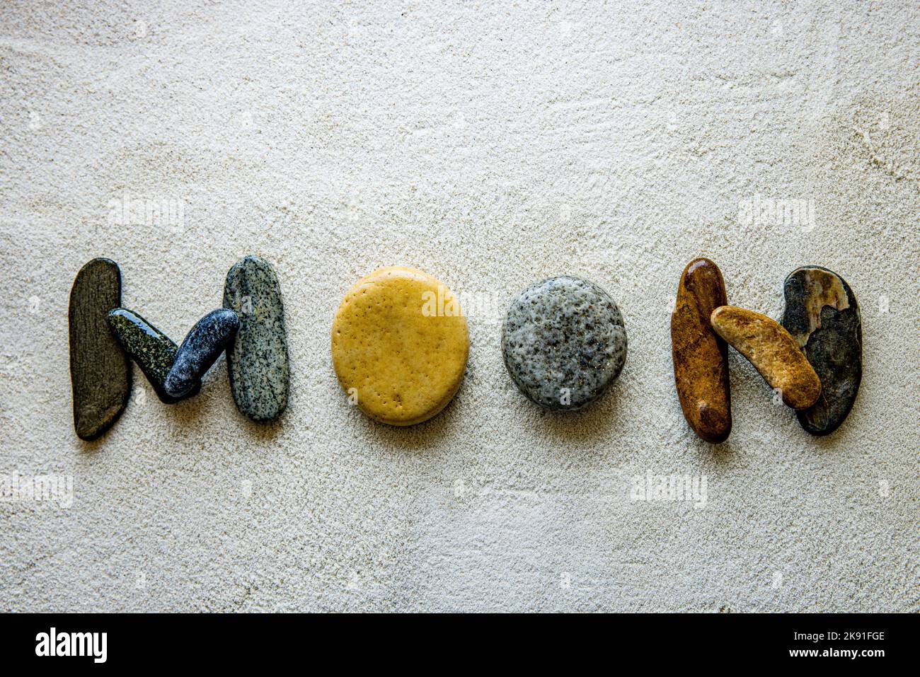 The word: MOON, written using colored stones on white sand Stock Photo ...