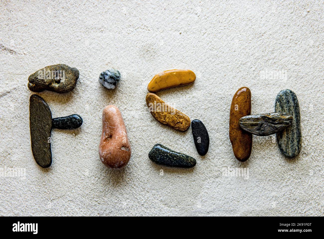 The word: FISH, written using colored stones on white sand Stock Photo ...