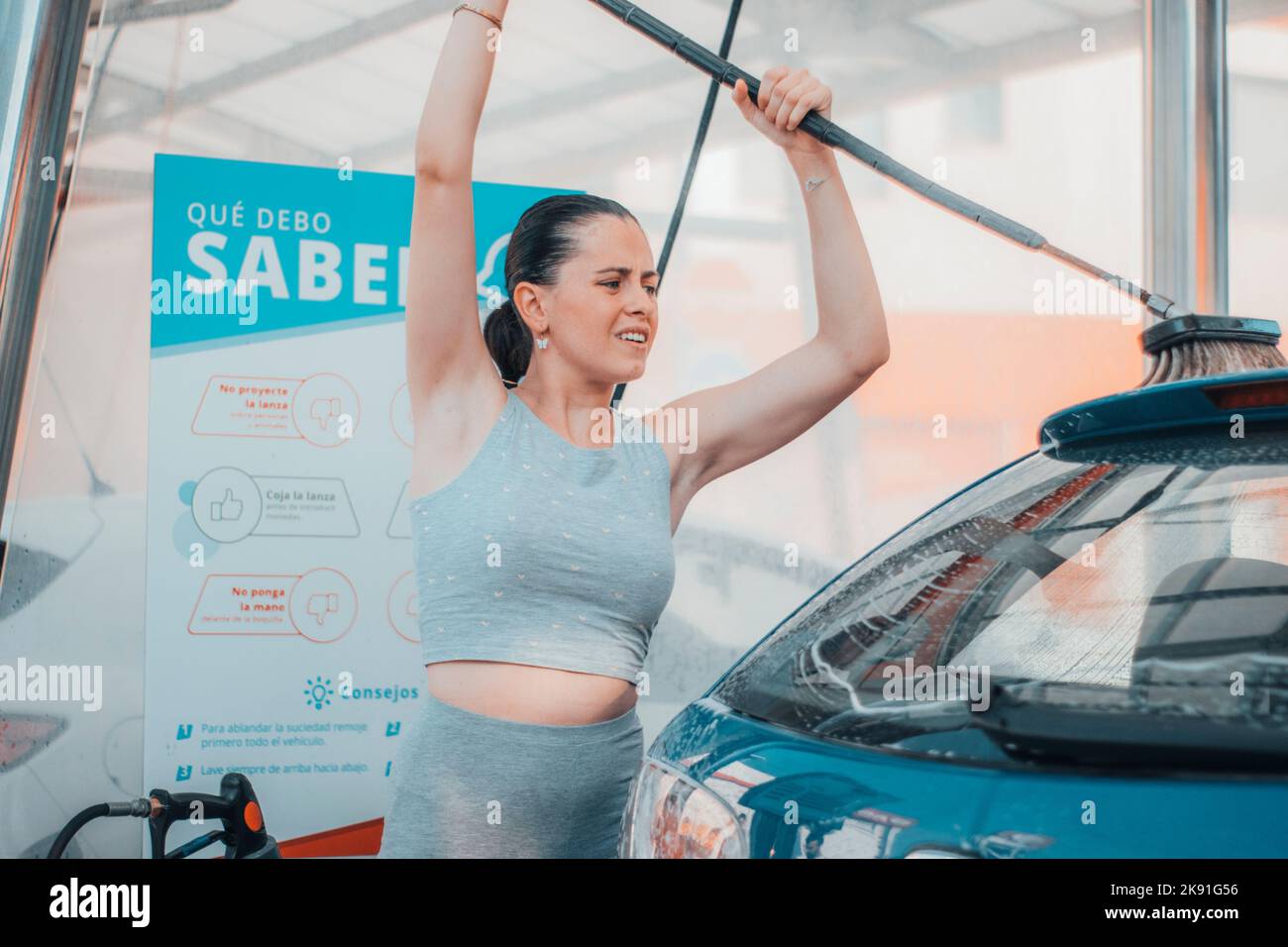 A closeup of a beautiful girl washing the car with a pressure washer ...