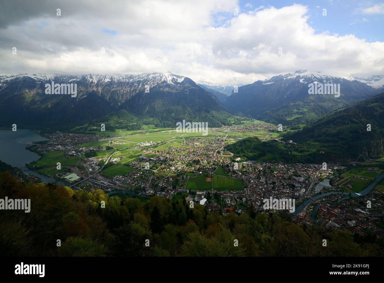 An aerial shot of Interlaken town surrounded by high mountains under a ...