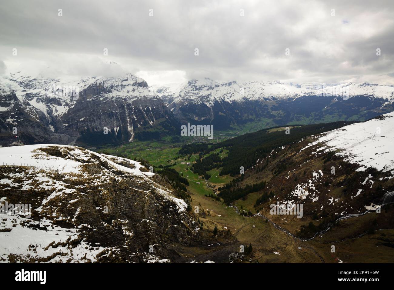 An aerial view of the snowy Swiss Alps covered with clouds against ...