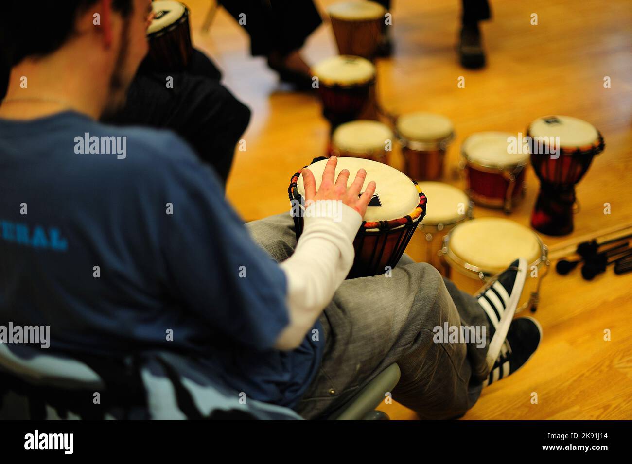 A high-angle rear of a male learning to play bongo indoors, bongos on ...