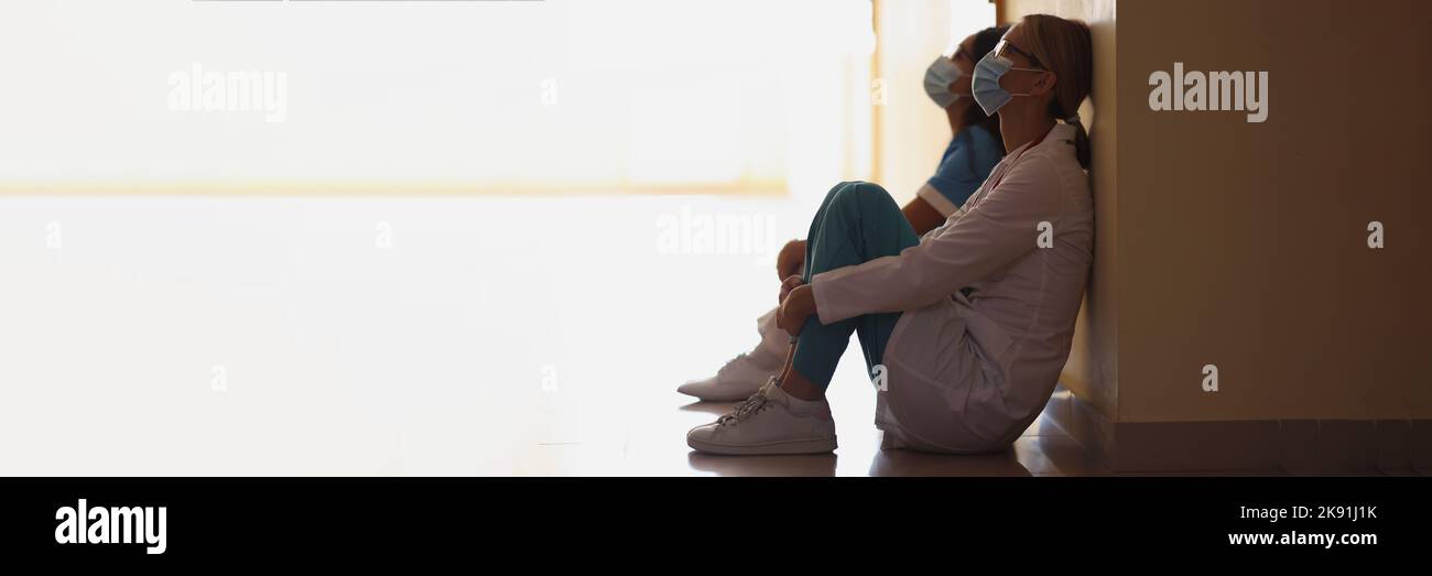 Exhausted nurses after hard long surgery sitting on floor in hall ...