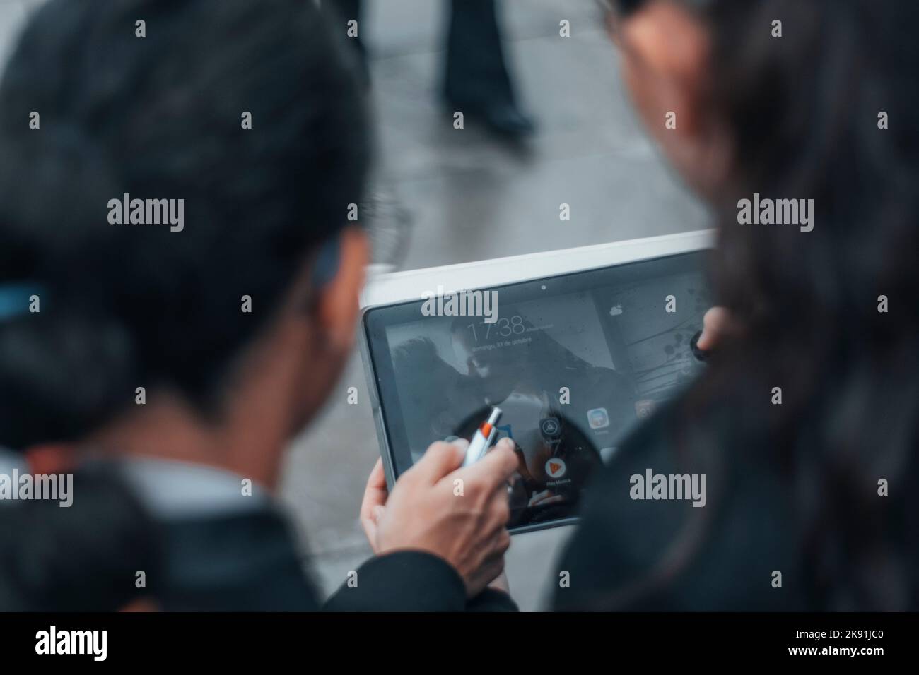 The back of the heads of two caucasian women pointing at the tablet ...