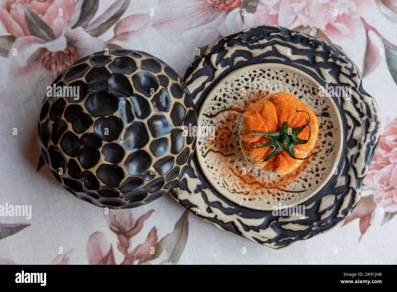 A top view of Burrata cheese covered in red pepper powder and decorated ...