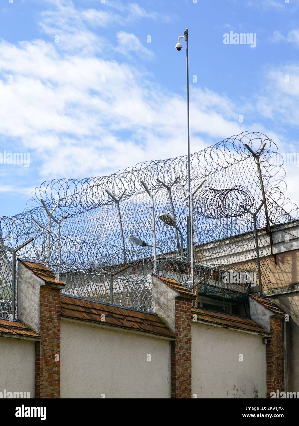 Lots of barbed wire over a brick fence around the perimeter of the ...