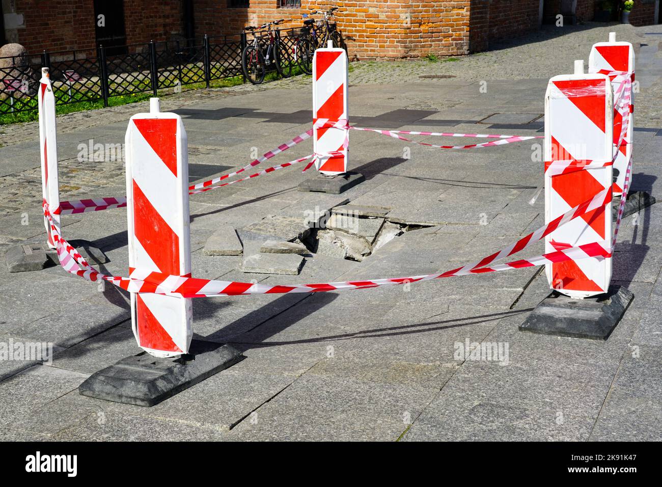 Collapse of pavement slabs on city street, restricted by red and white ...