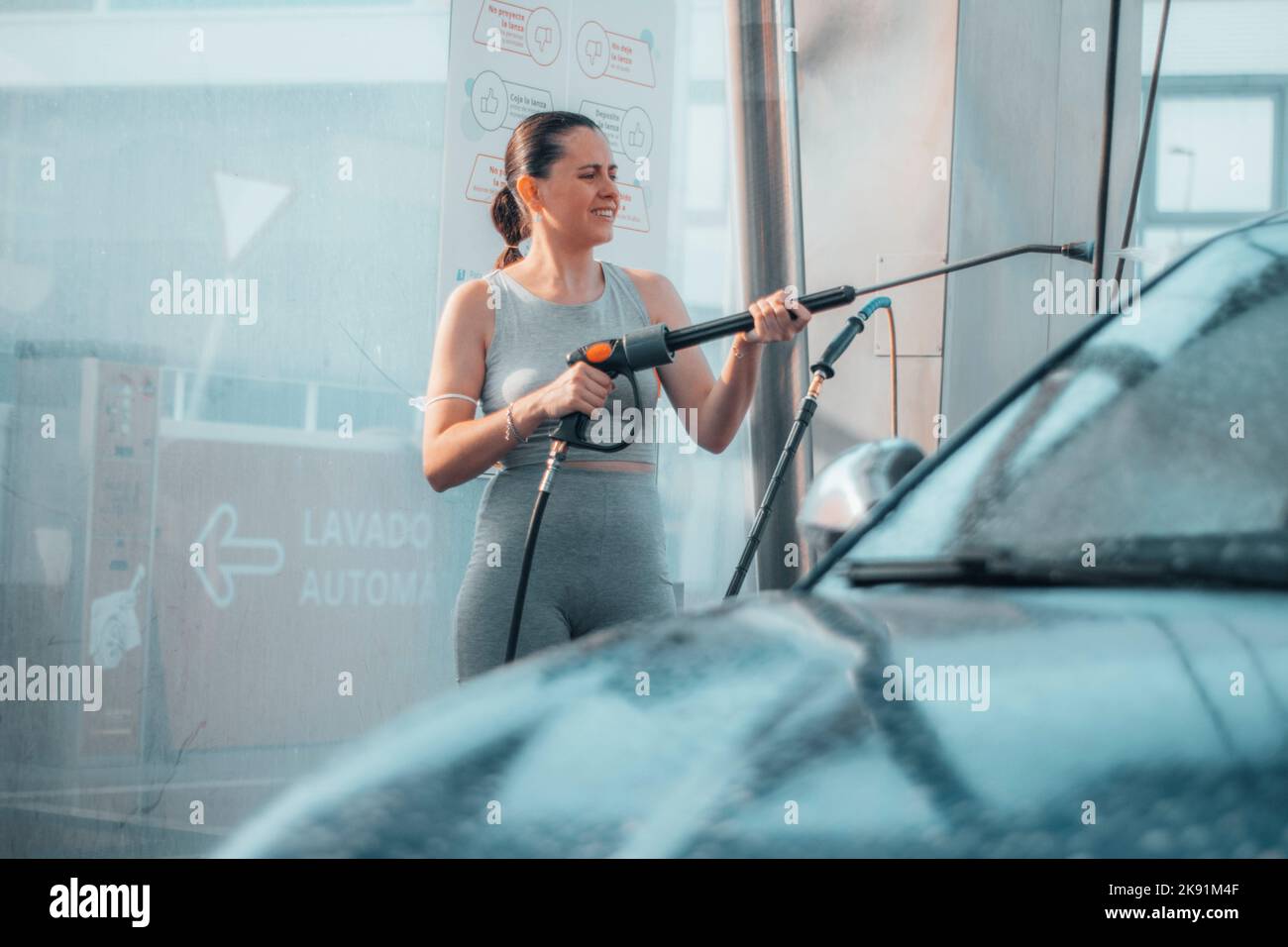 The young woman with a high-pressure washer in the car wash Stock Photo ...