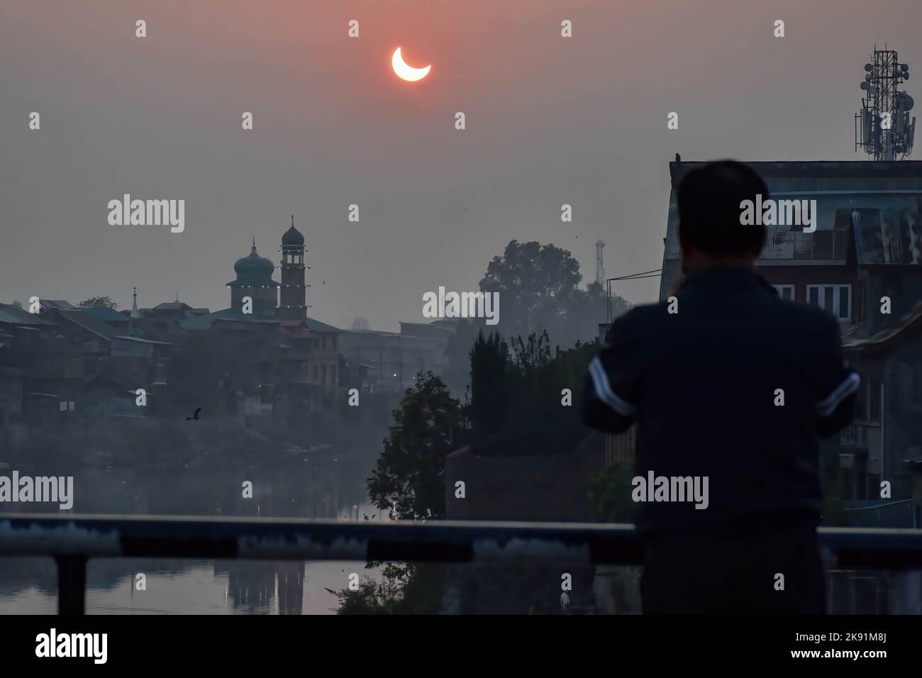 A man watches a partial solar eclipse in Srinagar. The partial solar ...