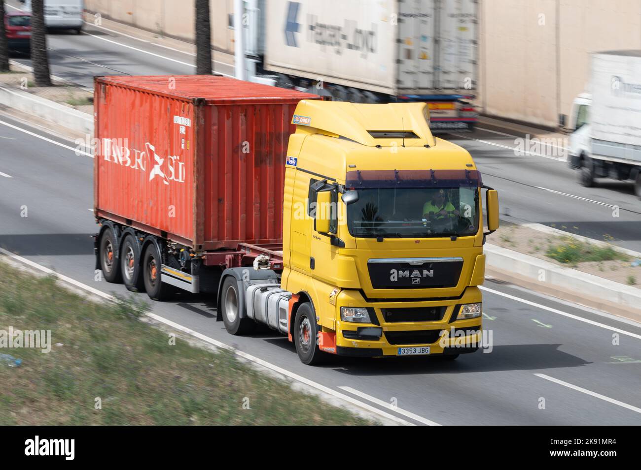 Yellow MAN TGX truck loading a red container trailer along Barcelona's ...