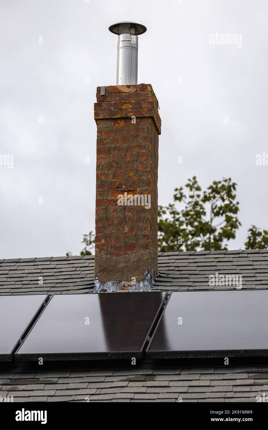 A vertical of a chimney and solar panels on an old New England home ...
