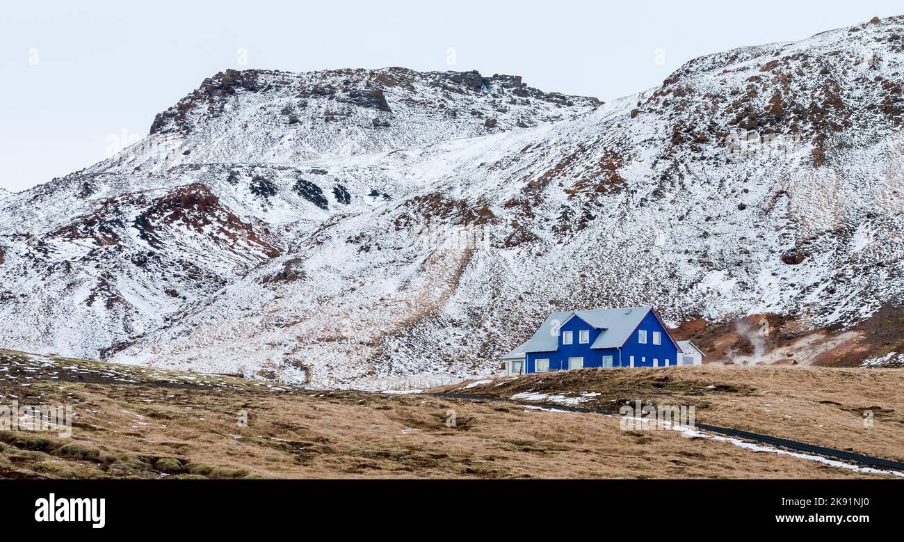 Icelandic landscape with blue chalet farm house. Mountains covered in ...