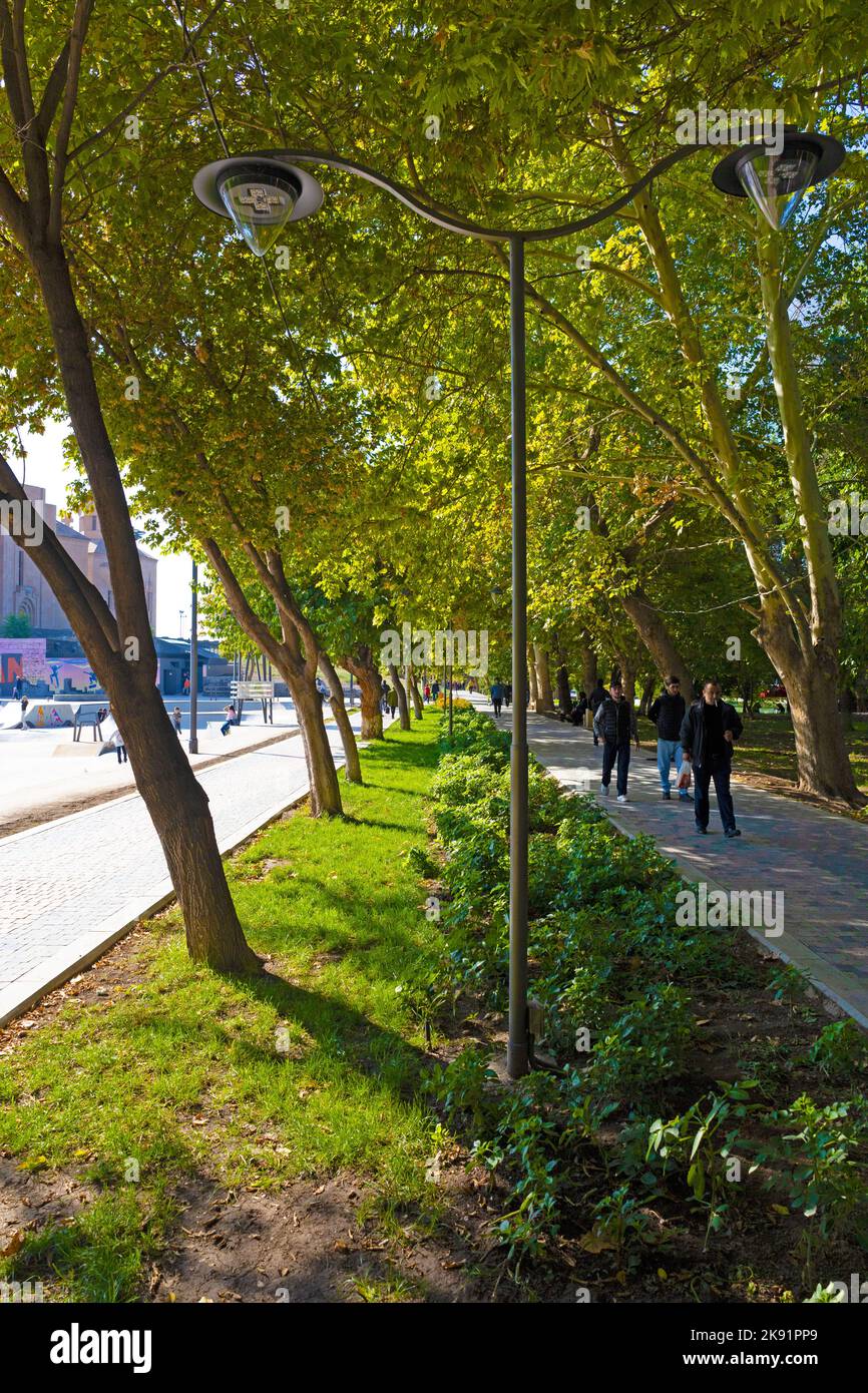 Lamppost in a park with people walking in the background. Light pole ...