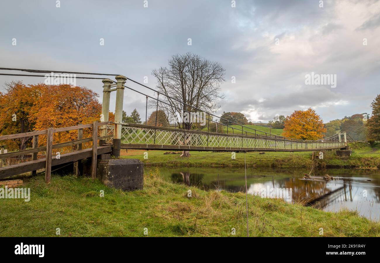 Autumn colours surround the Hebden Suspension Bridge spanning the River ...