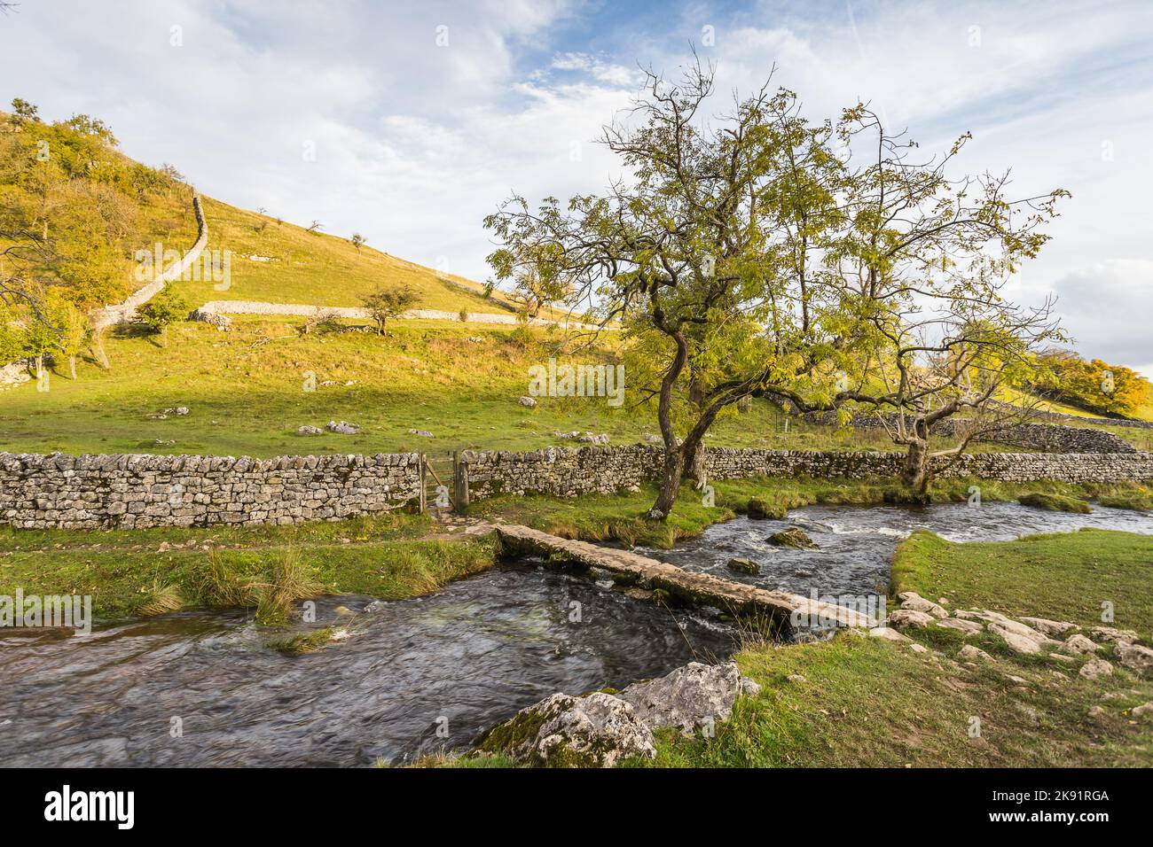 A narrow bridge spans the Malham Beck near Malham Cove in the Yorkshire ...